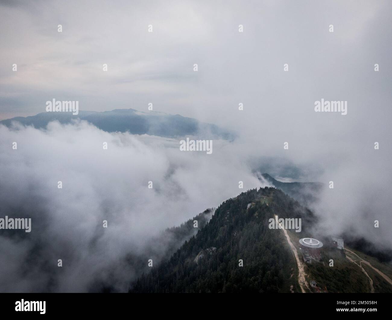 An aerial view of a dense green mountain forest covered with dense fog ...