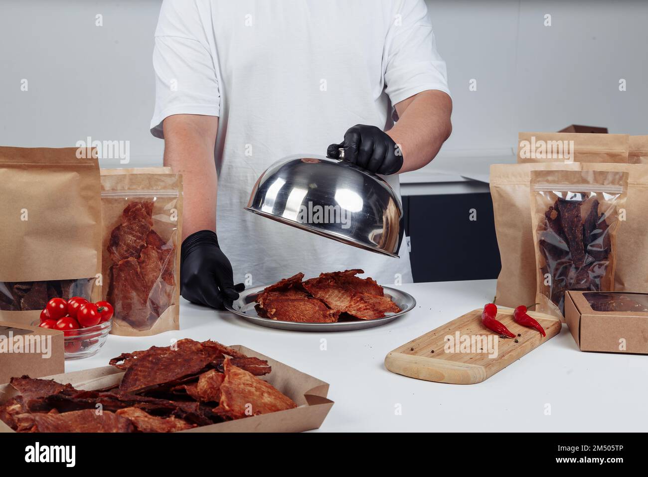 a guy puts dried meat in paper boxes in black gloves. High quality ...