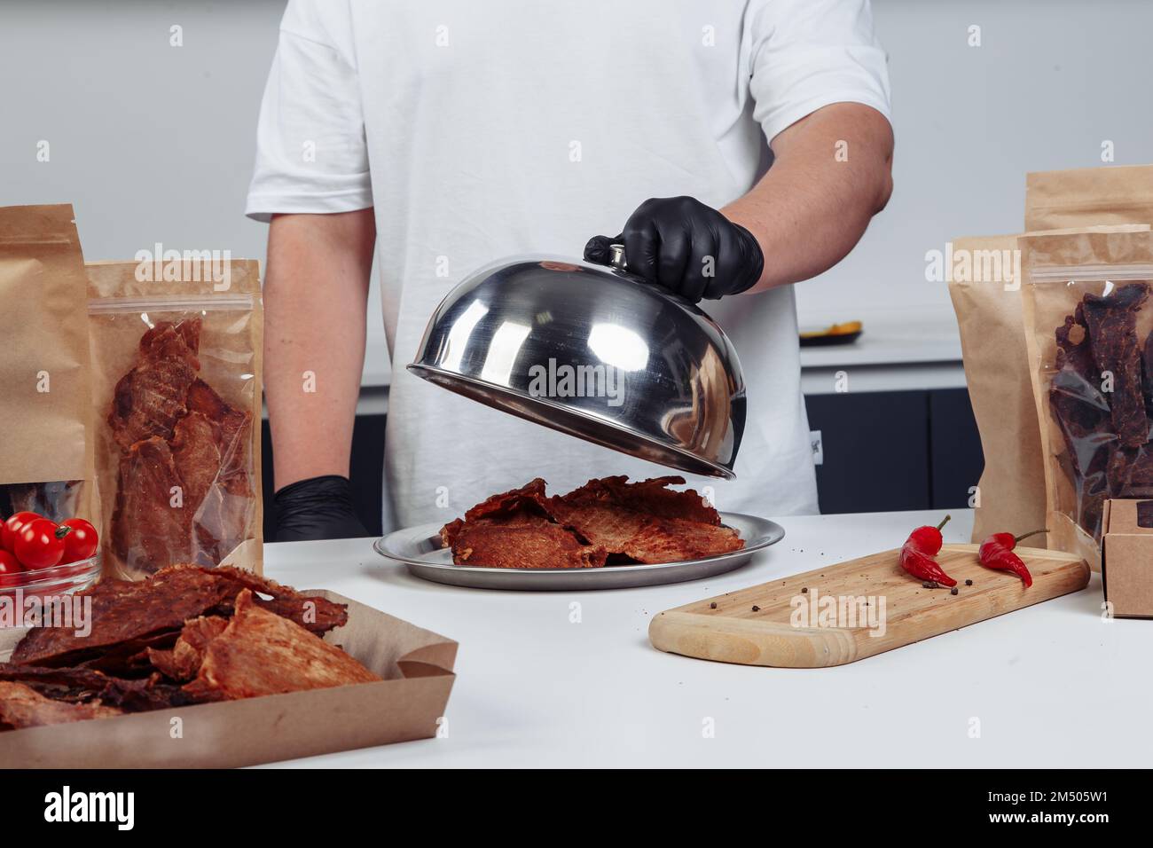 a guy puts dried meat in paper boxes in black gloves. High quality ...