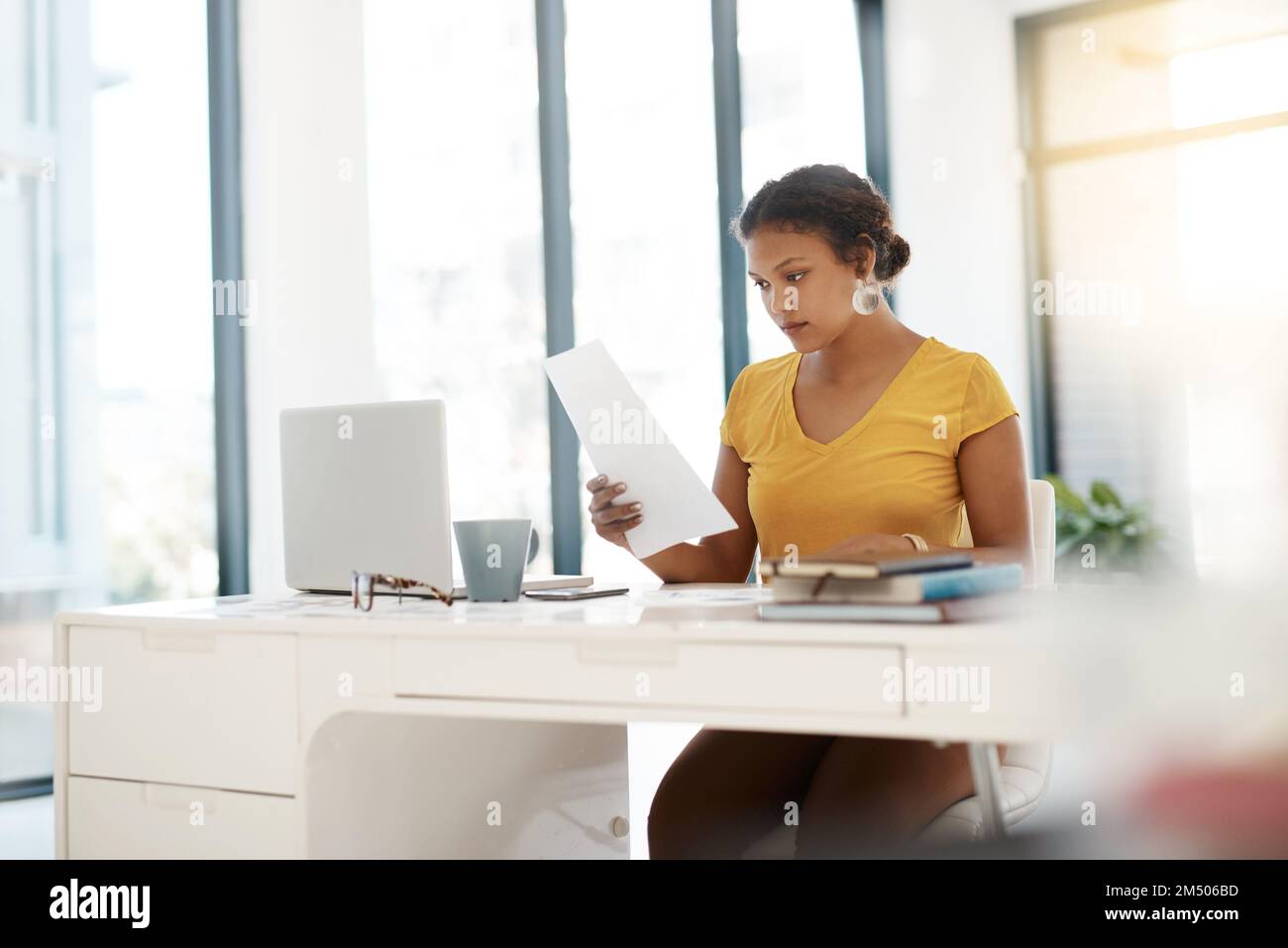 Dedication gets the job done. a young businesswoman reading a document ...