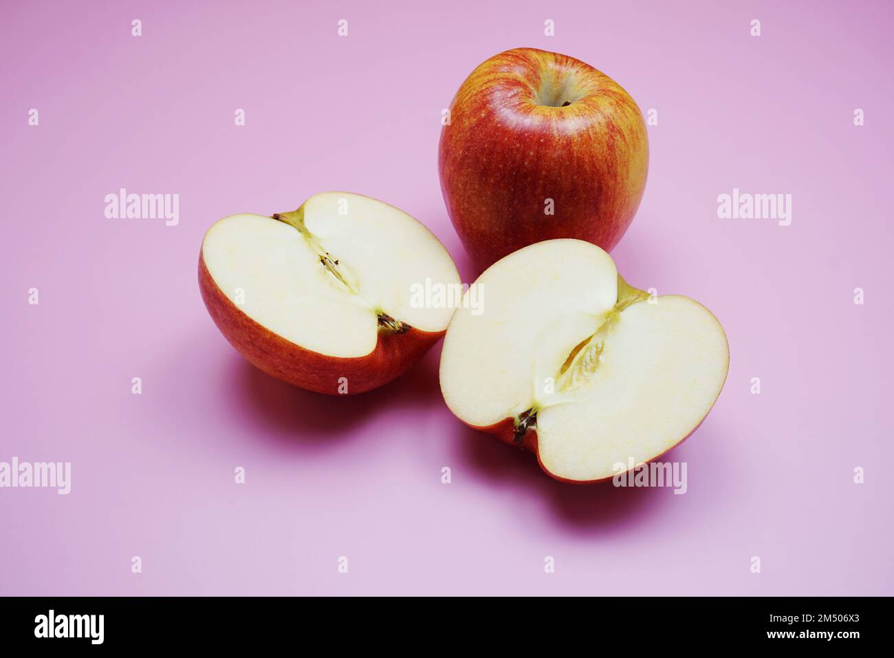 Apple cut half slices on pink background Stock Photo - Alamy