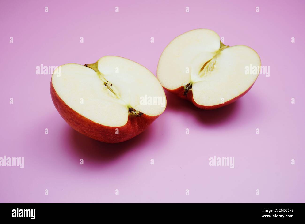 Apple cut half slices on pink background Stock Photo - Alamy