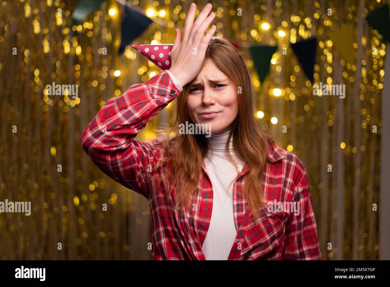 Student girl wearing red shirt at home looking with regretful look into ...