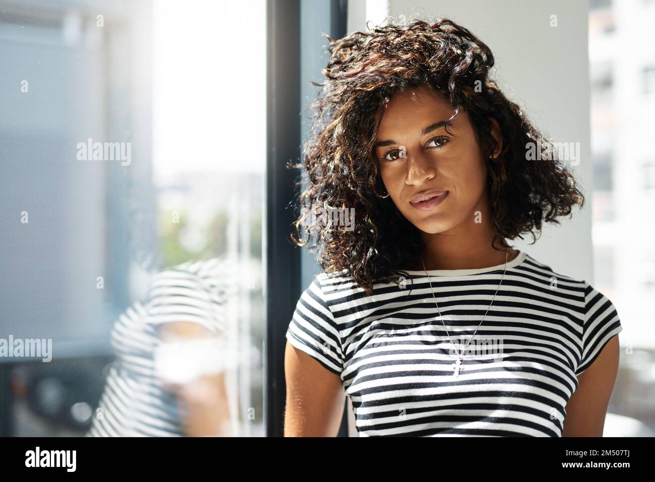 Enjoying the sun that comes through this window. Cropped portrait of an ...