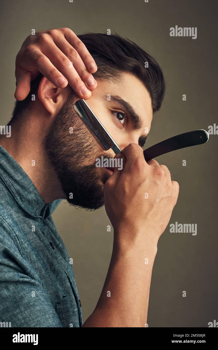 Work hard, beard harder. a handsome young man shaving with a straight ...