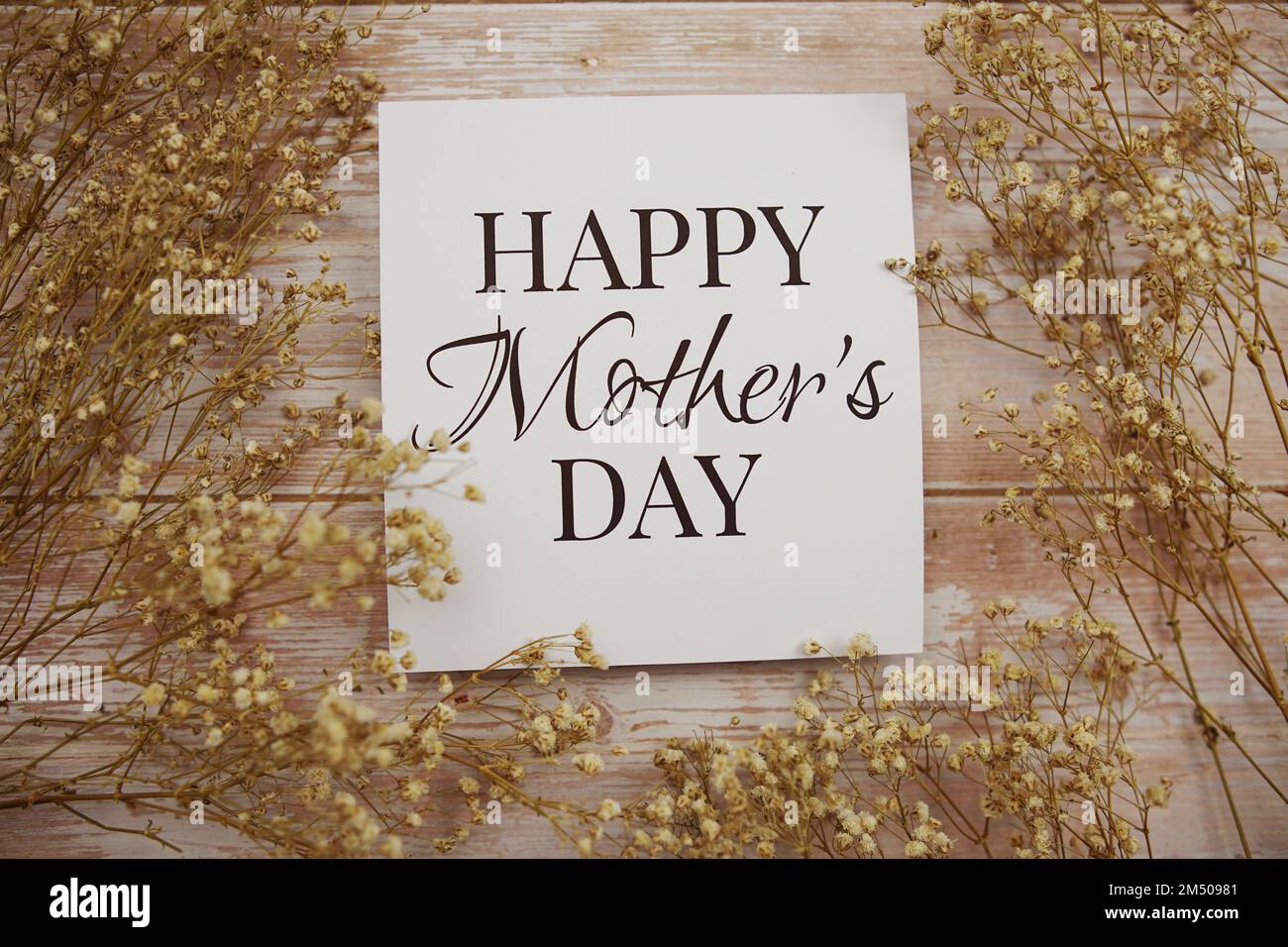 Happy Mother's Day text on paper card with flower decoration on wooden ...