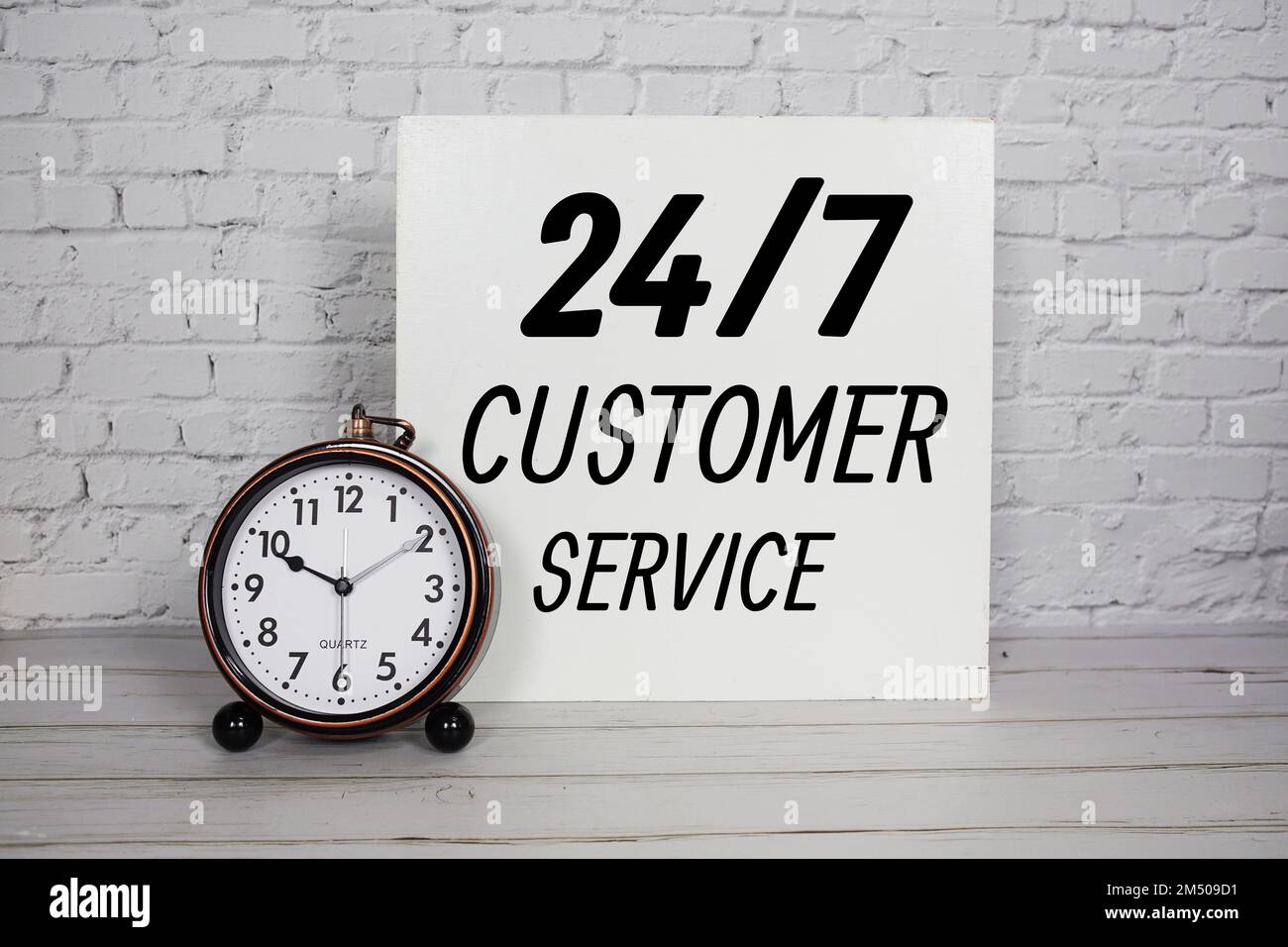 24/7 Customer Service alphabet letters and alarm clock on white brick ...