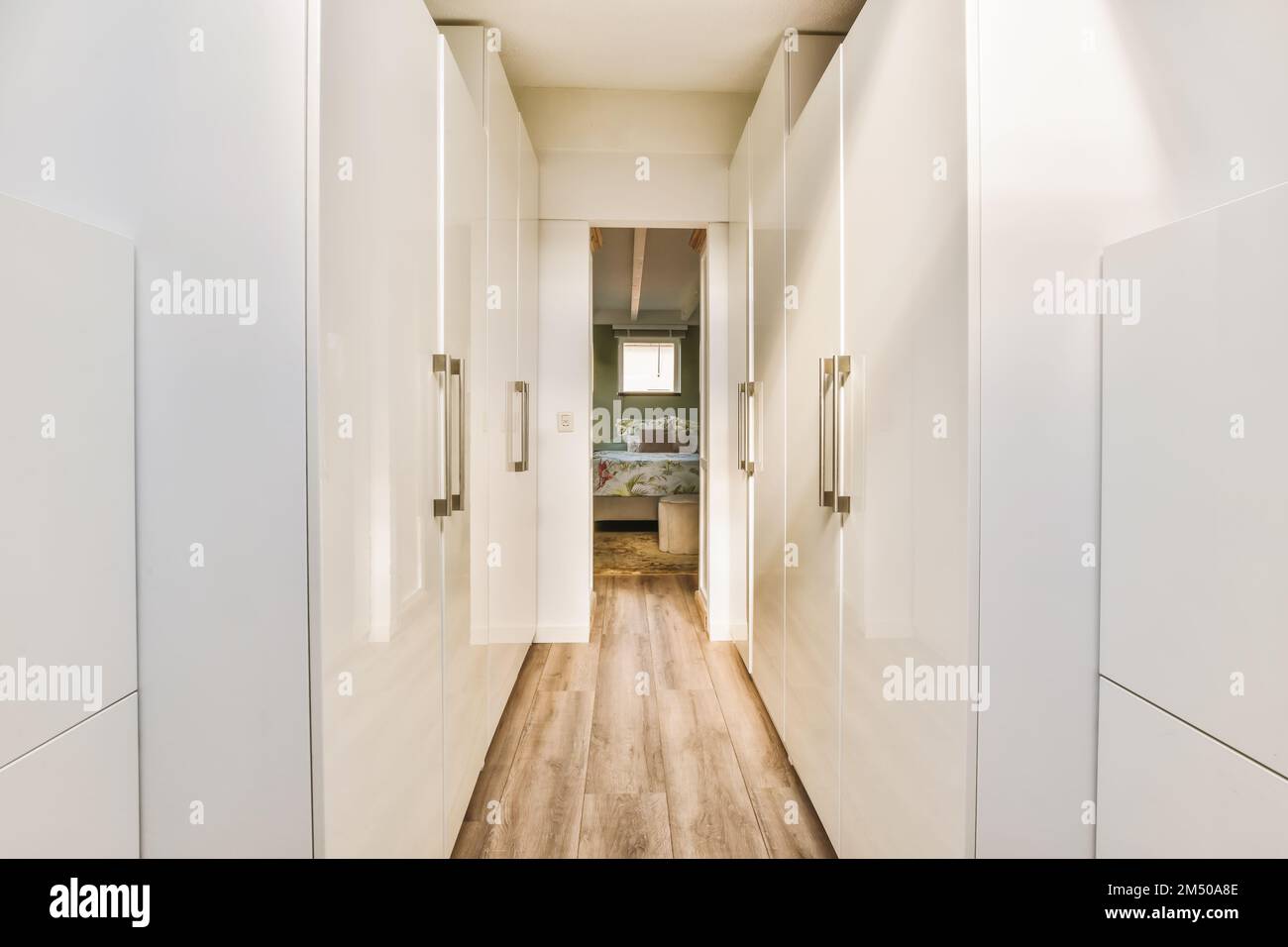 a long narrow hallway with white walls and wood flooring the room is ...