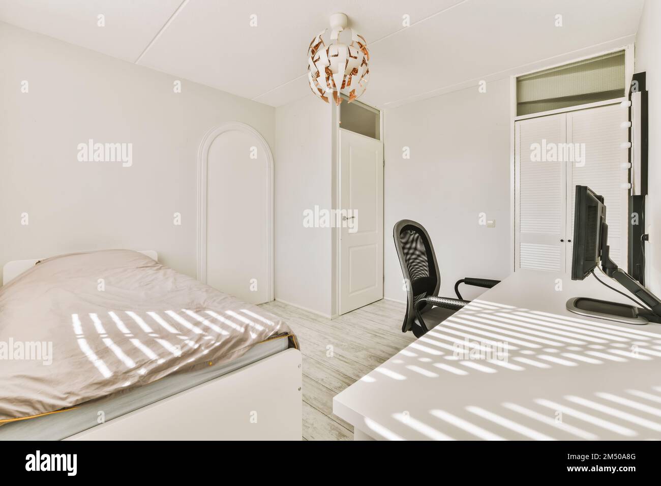 a bedroom with a bed, desk and computer monitor on the wall in front of ...