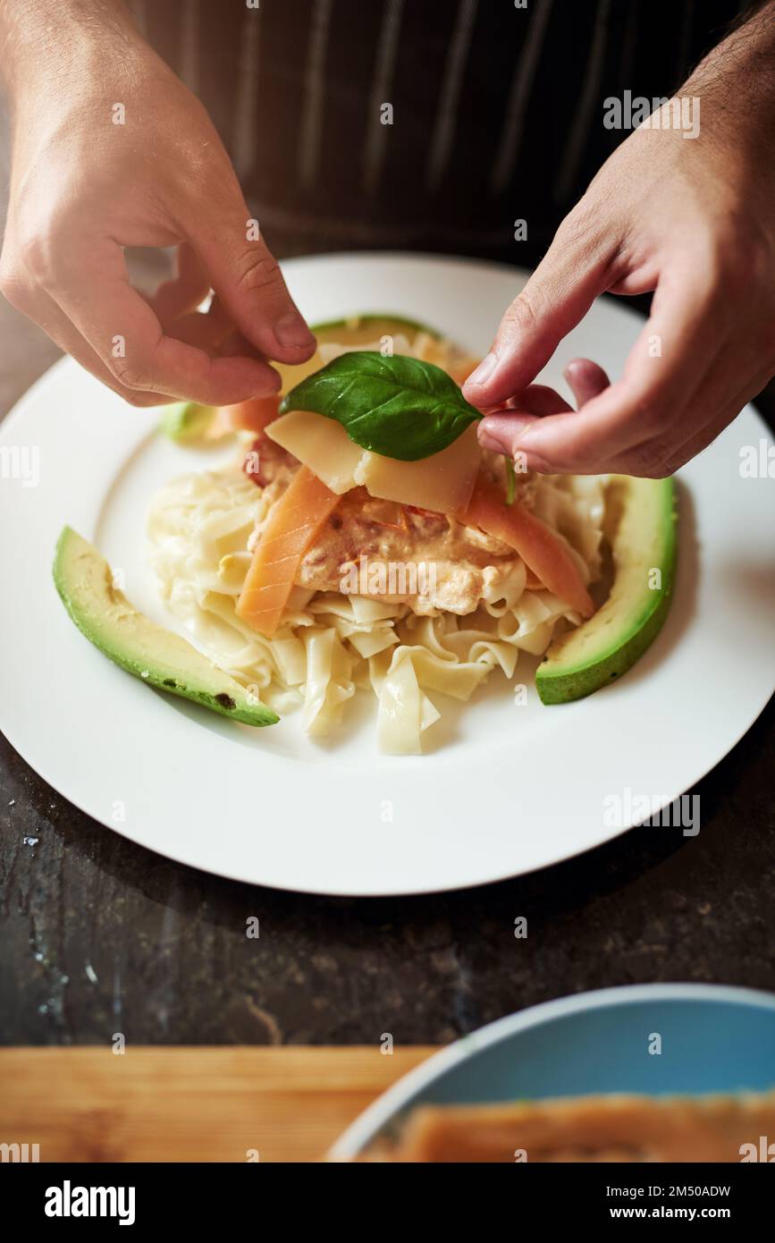 The final touch. an unrecognizable young man preparing food in the ...