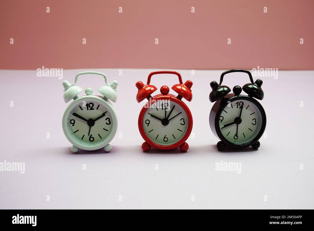 Alarm clocks with different time composition on pink background Stock ...