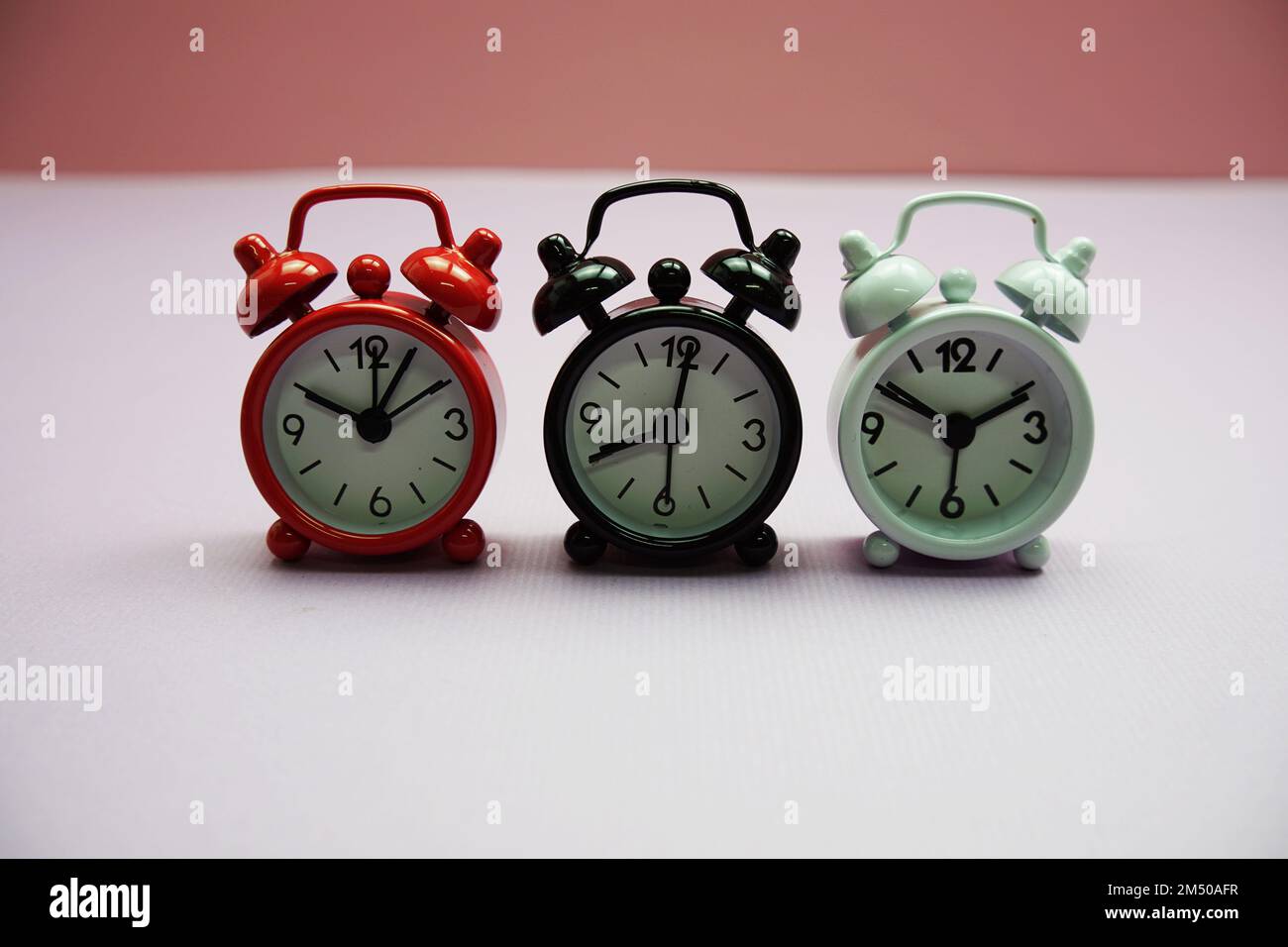 Alarm clocks with different time composition on pink background Stock ...