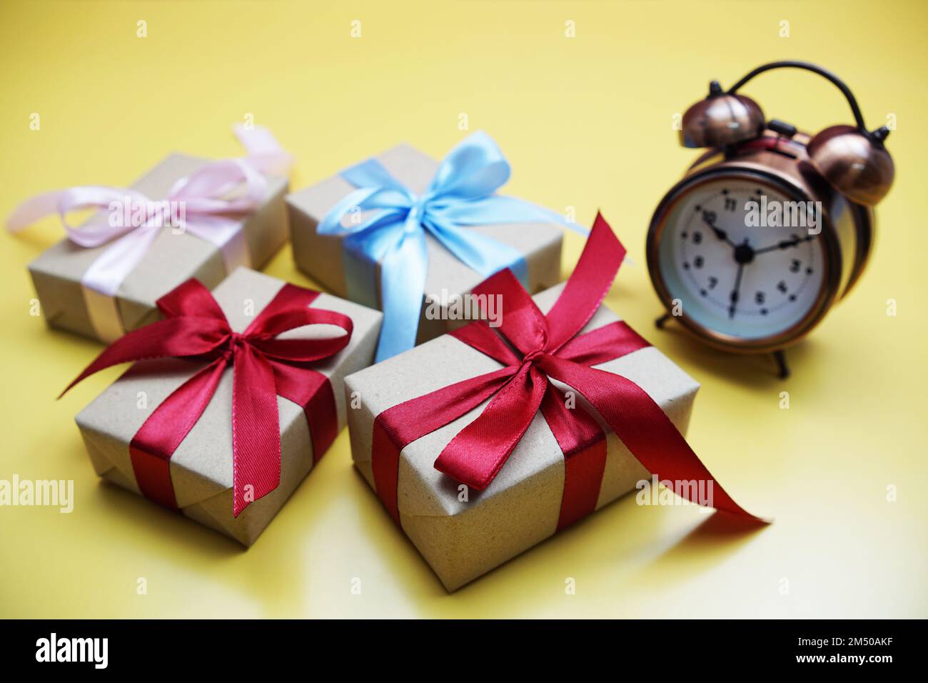 Gift boxes and alarm clock on yellow background Stock Photo - Alamy