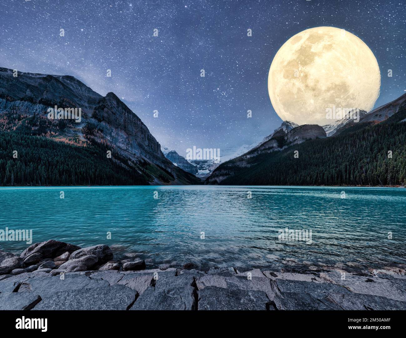 Big moon glowing over rocky mountains and starry on Lake Louise in the ...