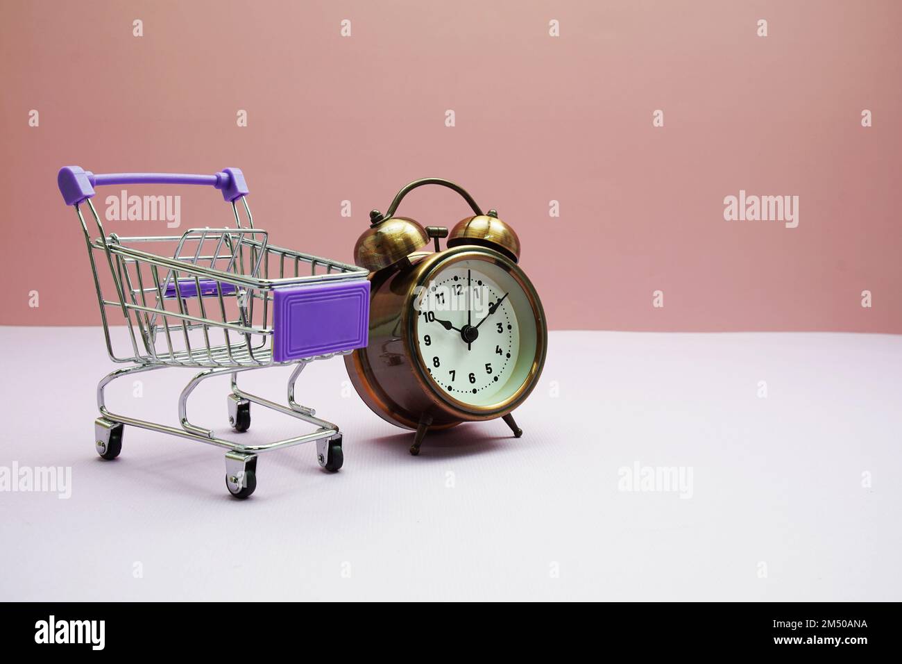 Shopping Mini Trolley cart and alarm clock on pink background Stock ...