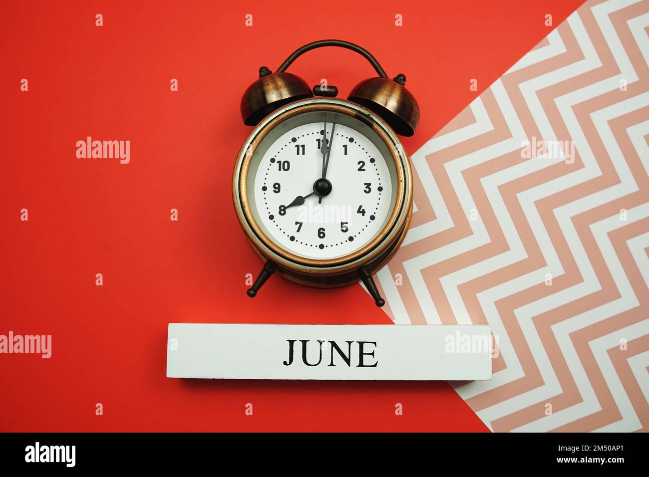 June and alarm clock on red background Stock Photo - Alamy
