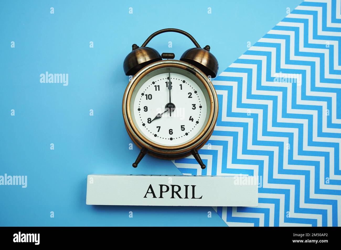 April and alarm clock on blue background Stock Photo - Alamy
