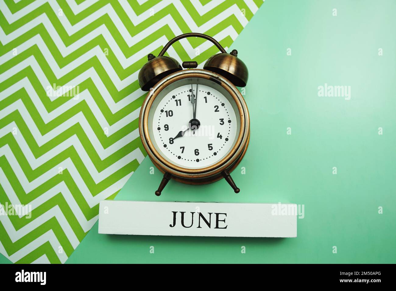 June and alarm clock on green background Stock Photo - Alamy