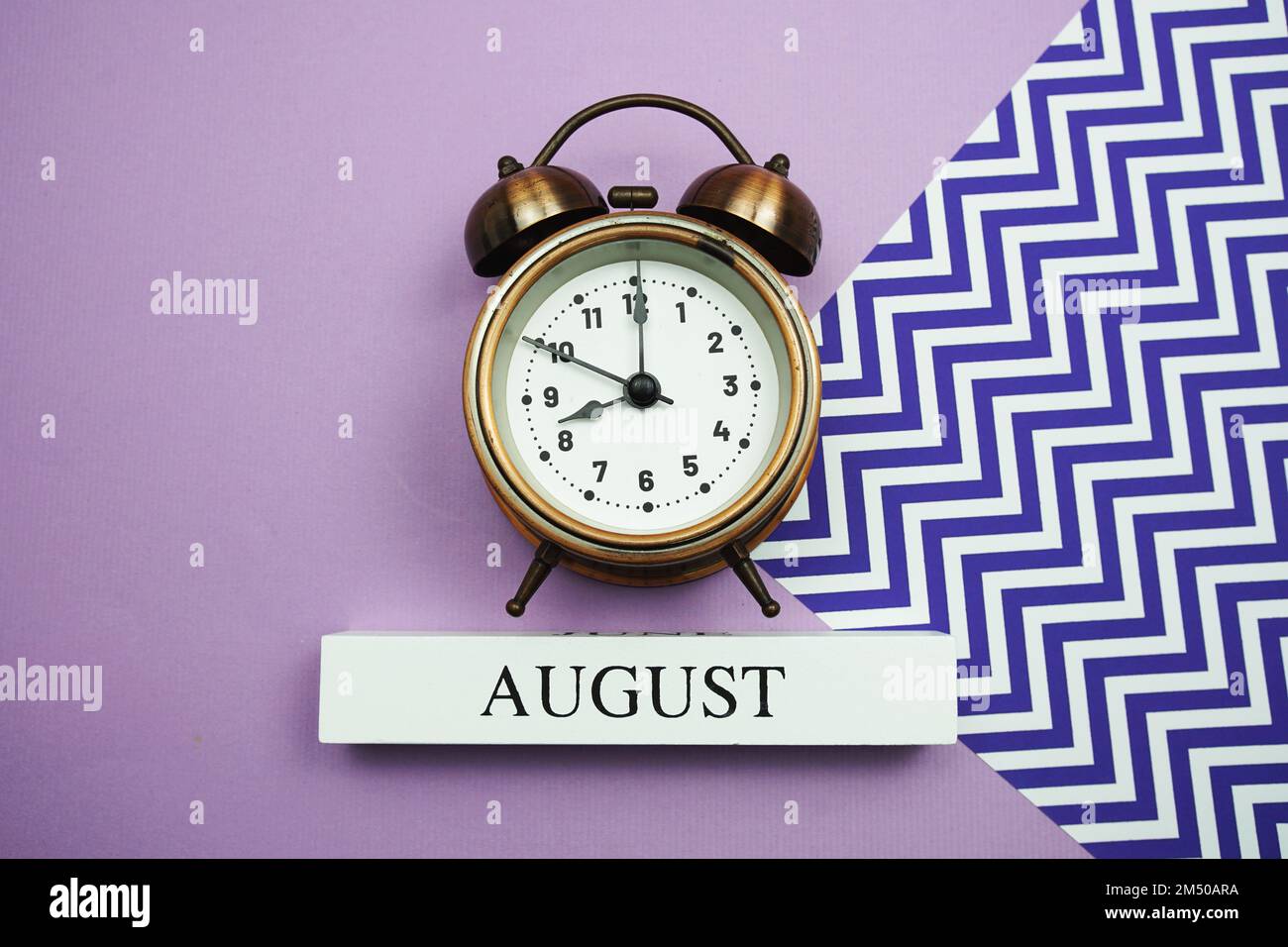 August and alarm clock on purple background Stock Photo - Alamy