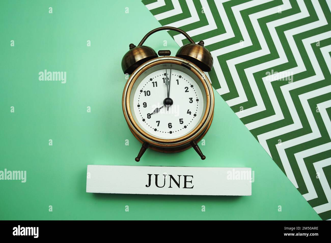June and alarm clock on green background Stock Photo - Alamy