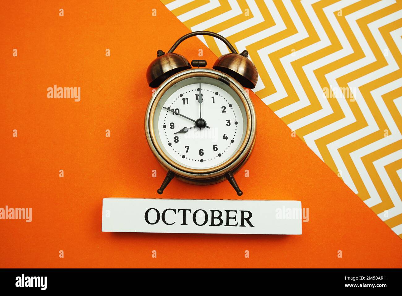 October and alarm clock on orannge background Stock Photo - Alamy