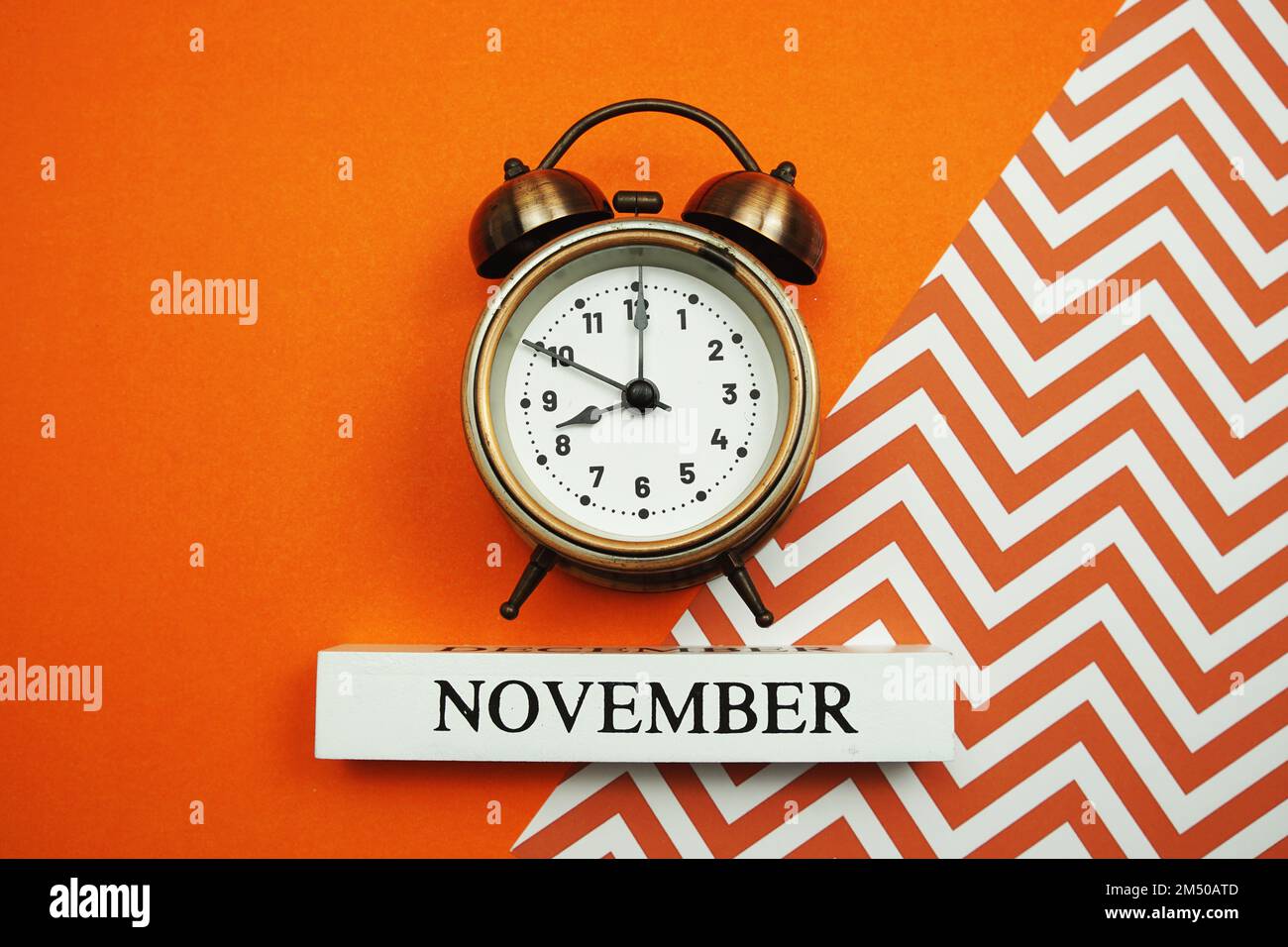 November and Alarm clock on orange background Stock Photo - Alamy
