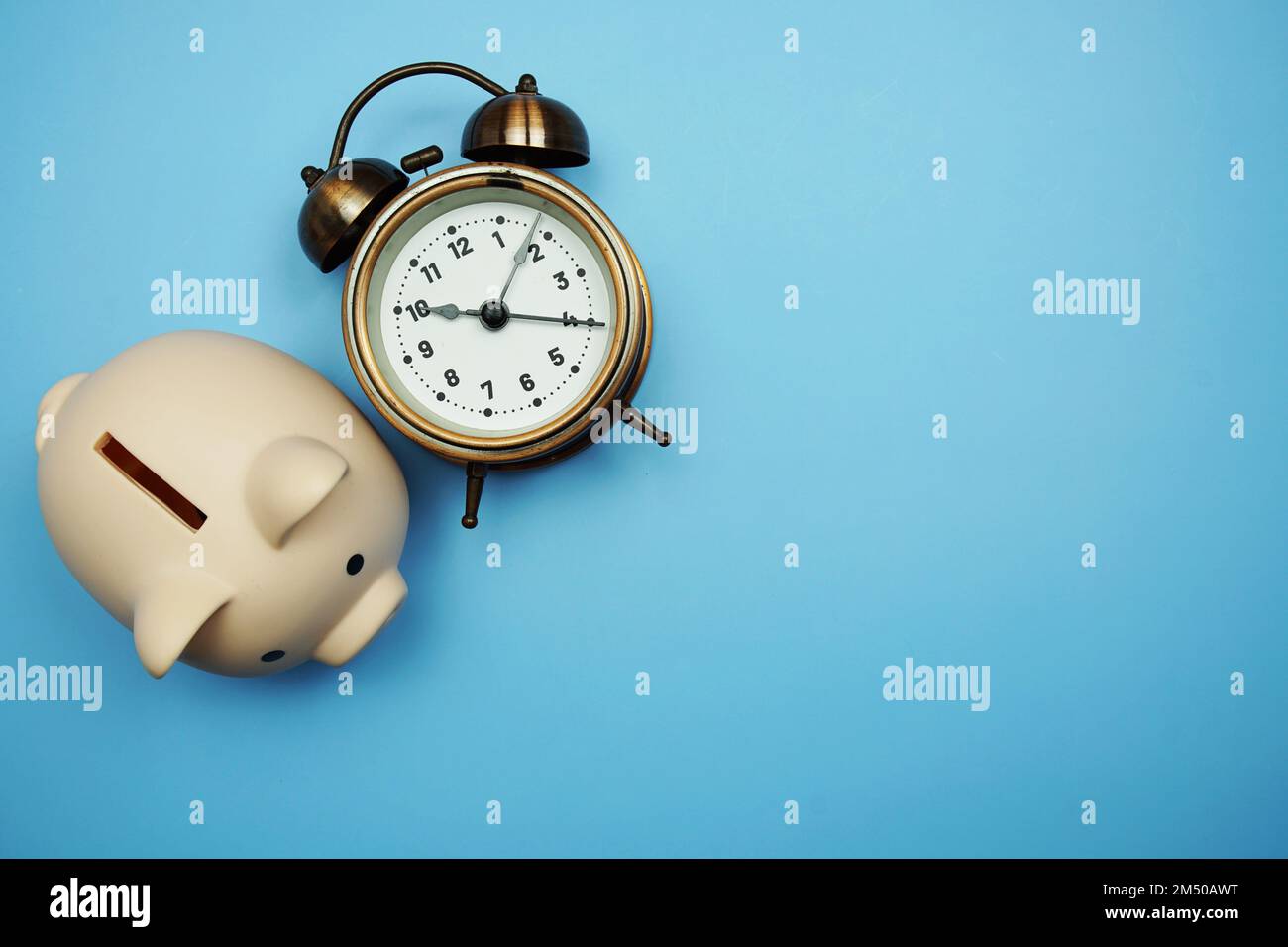 Piggy bank and alarm clock with space copy on blue background Stock ...