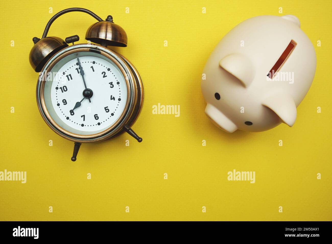 Piggy bank and alarm clock with space copy on yellow background Stock ...