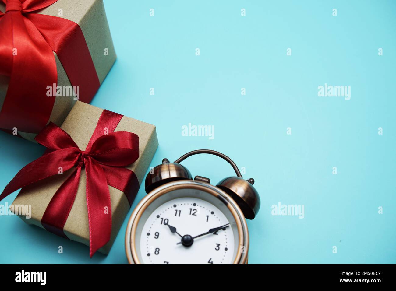 Gift boxes with red ribbon and alarm clock on blue background Stock ...