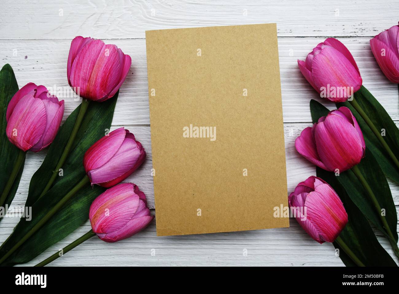 Empty paper card with pink tulip flower and alarm clock flat lay on ...
