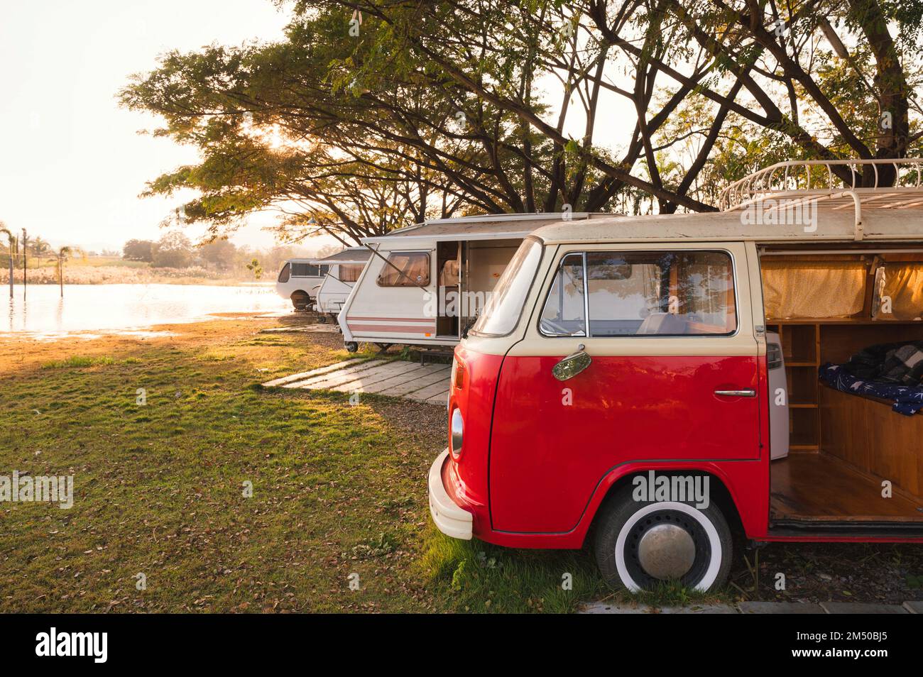 Retro camper van parked in campground on lakeside in the sunset at ...