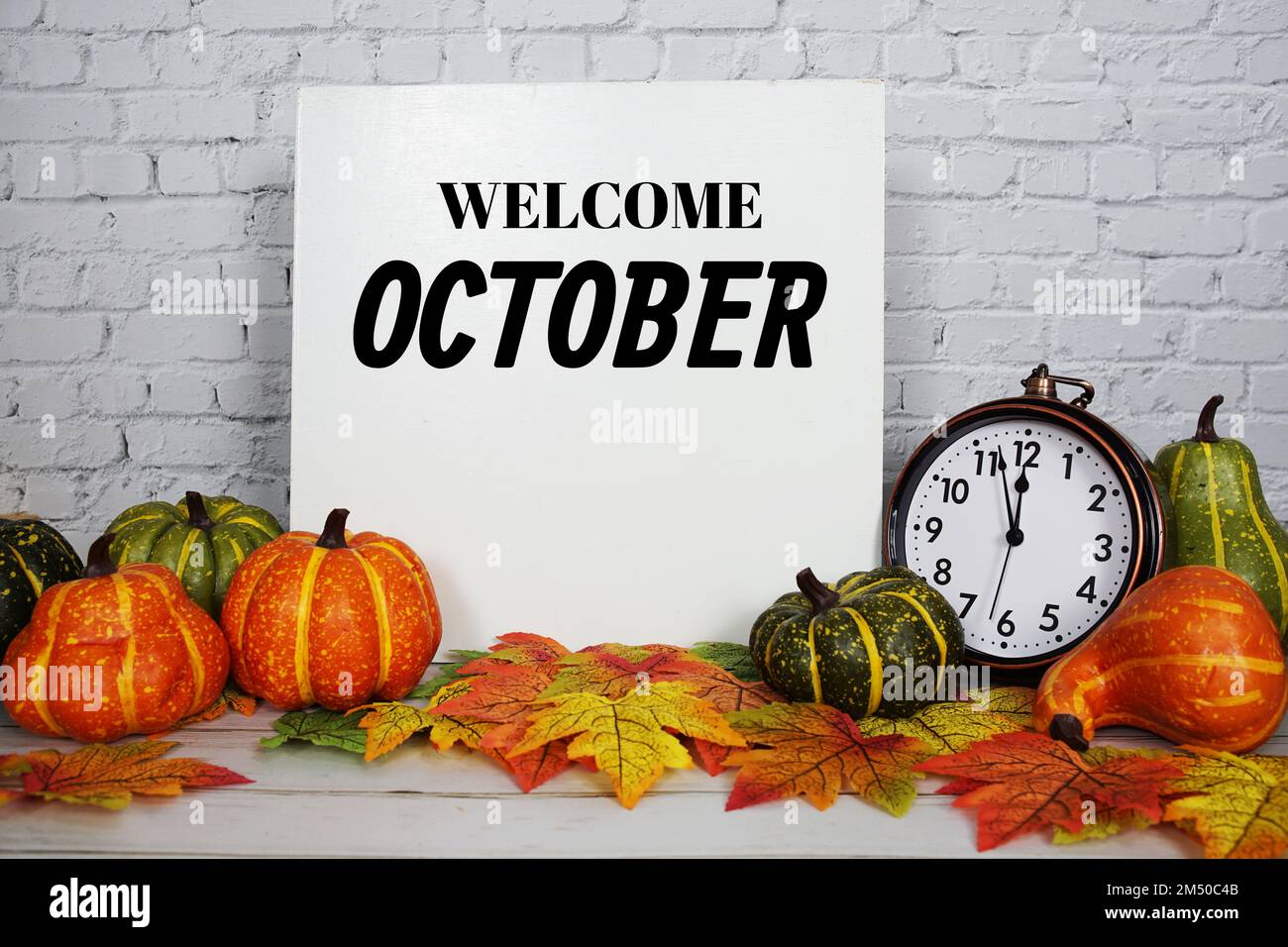 Welcome October text message with alarm clock, pumpkin and maple leaf ...