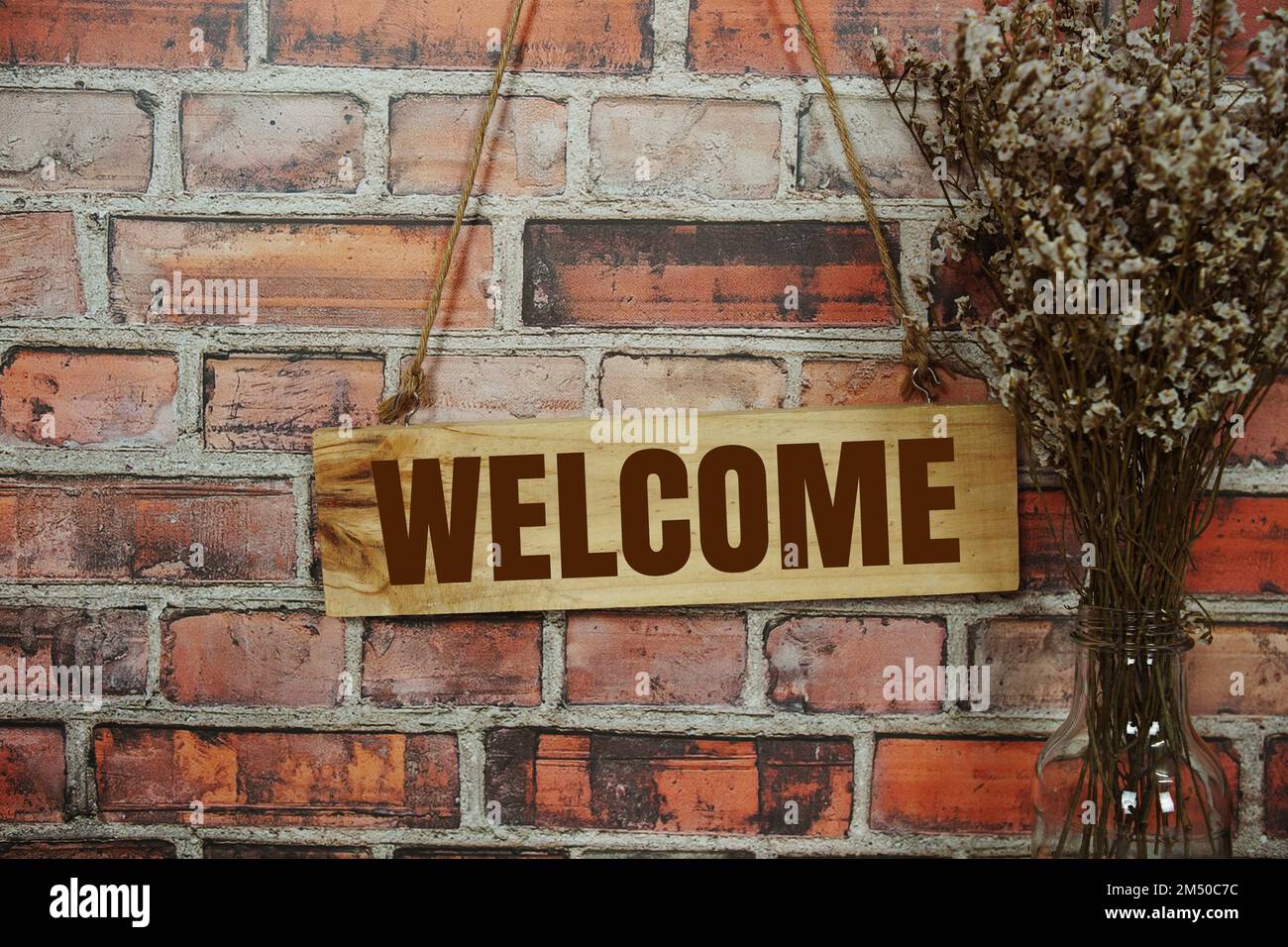 Welcome sign text message on wooden board hanging on old brick wall ...