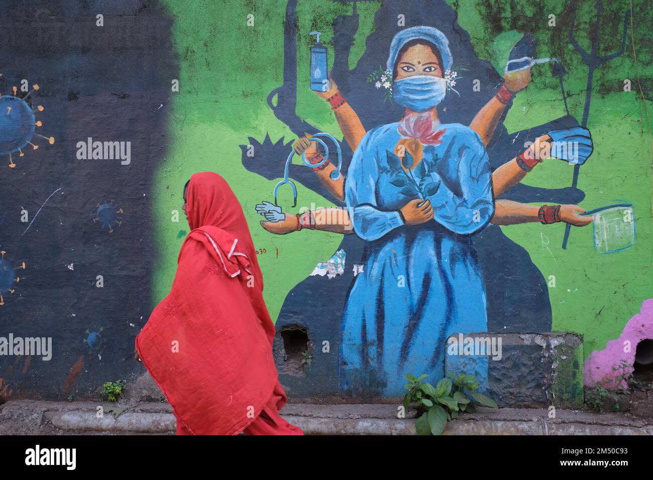 A sari-clad woman passes Covid-19 themed wall painting in the Byculla ...