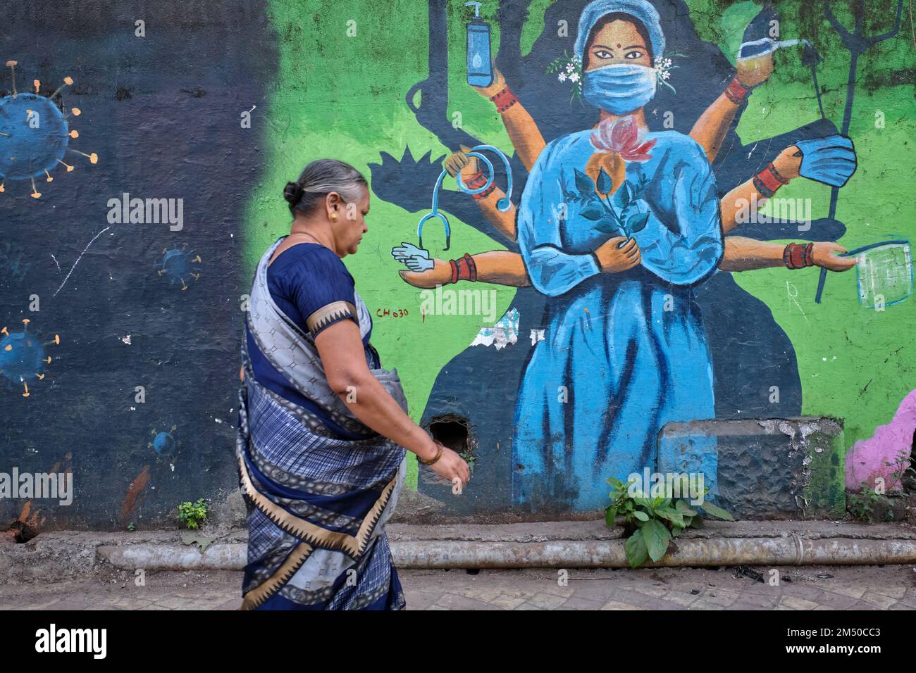 A sari-clad woman passes Covid-19 themed wall painting in the Byculla ...
