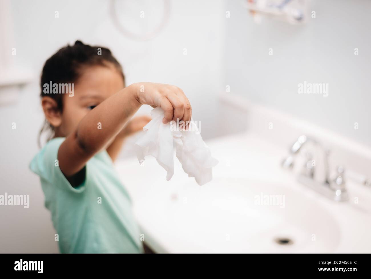 A cute preschool girl practicing good hygiene using the bathroom sink ...