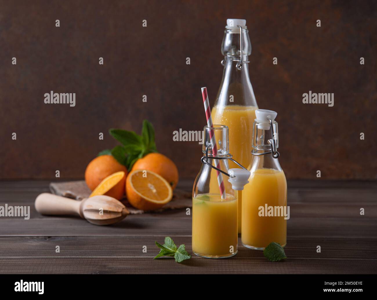 fresh orange juice in three bottles with citrus fruits on a brown ...