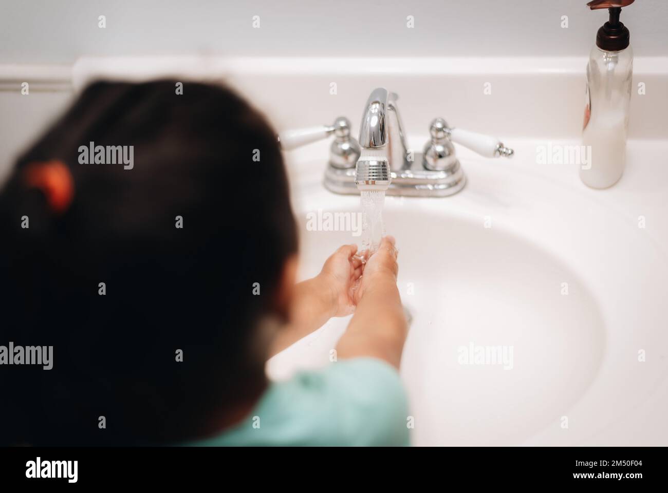 A cute preschool girl practicing good hygiene using the bathroom sink ...