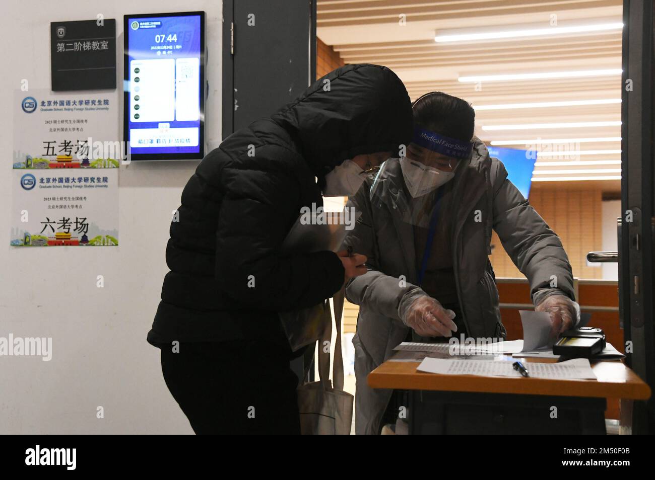Beijing, China. 24th Dec, 2022. An examinee (L) signs in at an ...