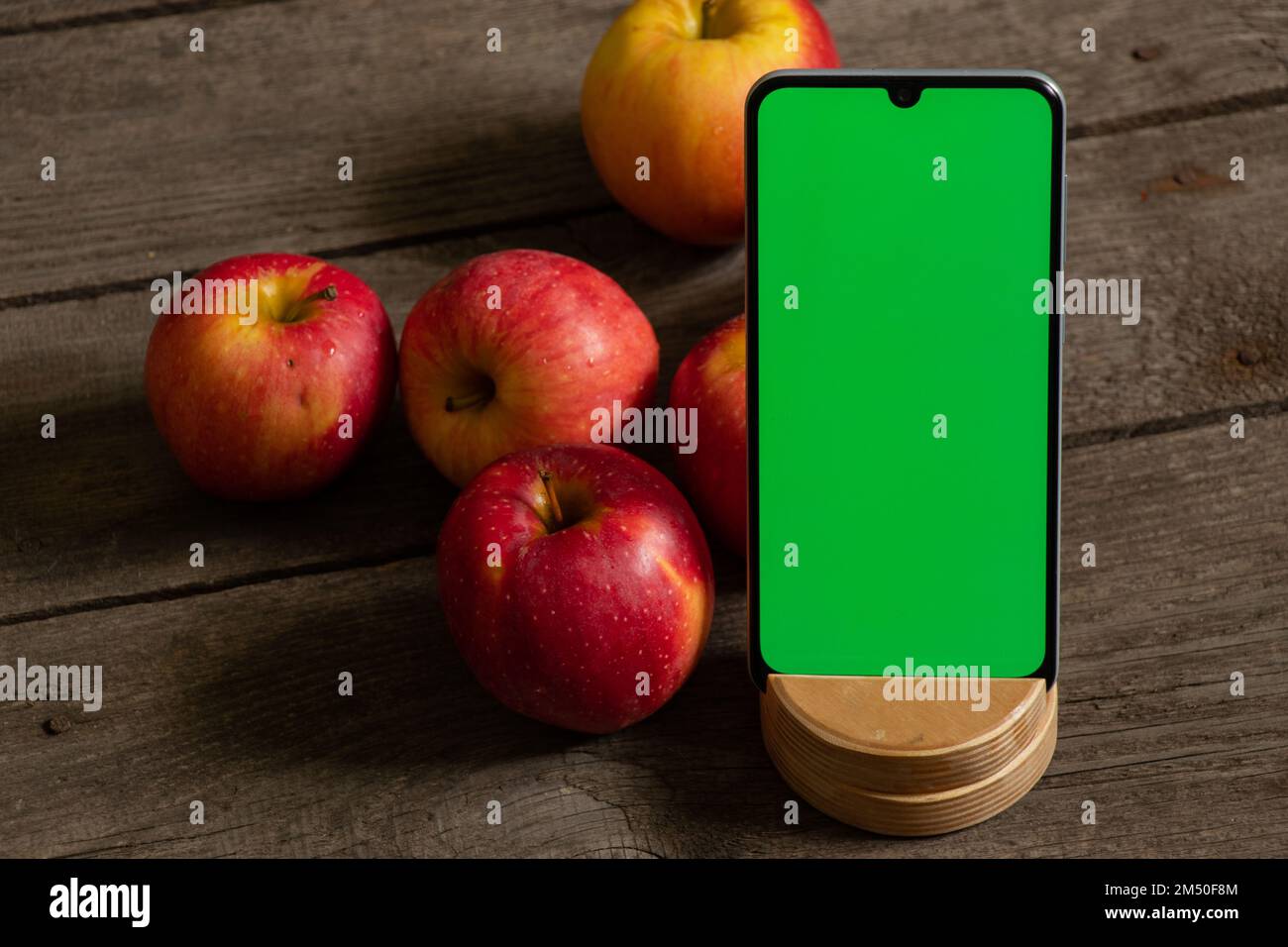 phone with a green screen and red apples are scattered Stock Photo - Alamy