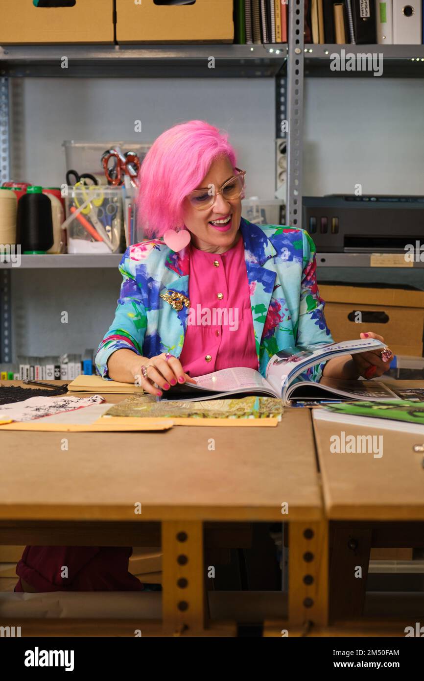 Tailor with pink hair taking ideas from fashion magazines Stock Photo ...