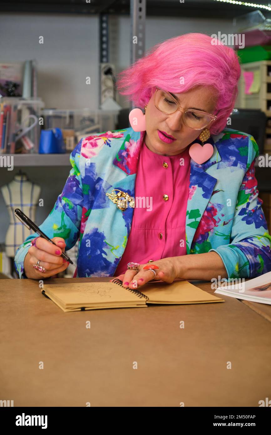 Dressmaker with pink hair and colorfull clothes drawing new layout ...