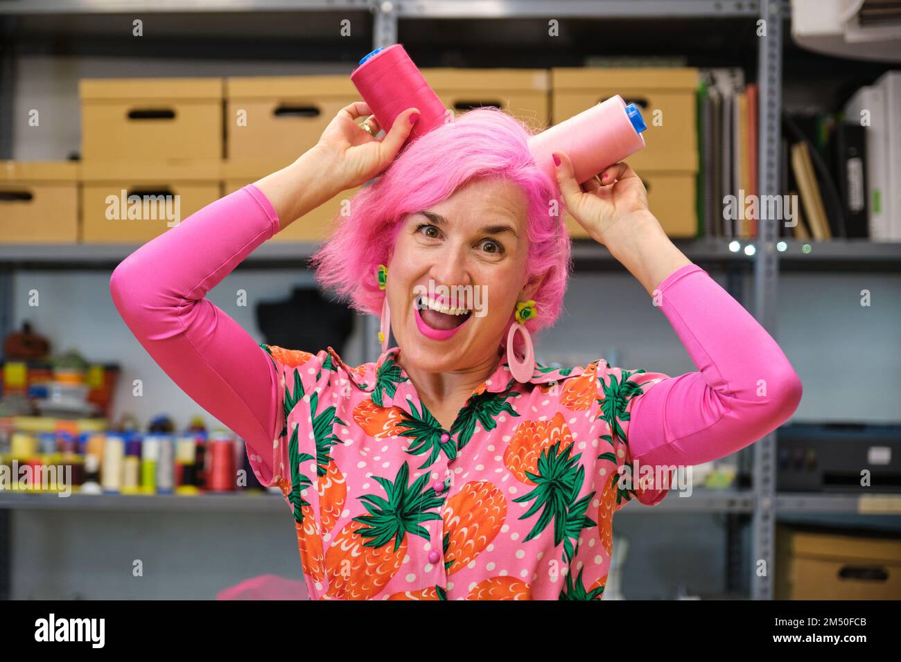 Dressmaker with pink hair making funny faces with sewing thread reels ...