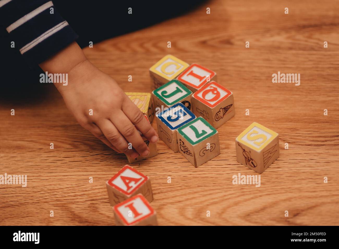 A preschool girl, playing with wooden letter blocks at home on the ...