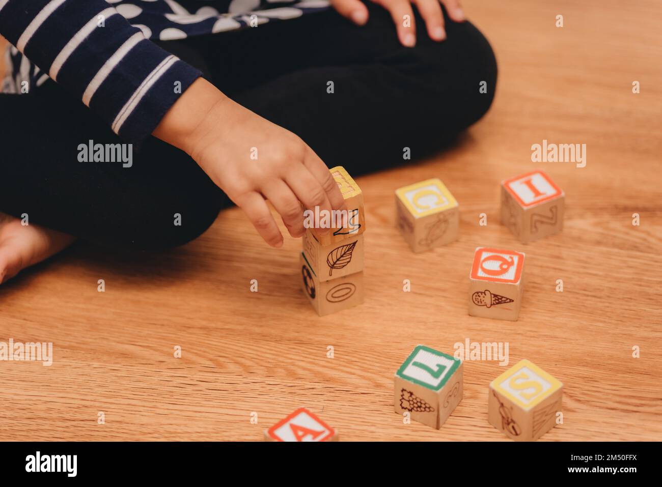 A preschool girl, playing with wooden letter blocks at home on the ...