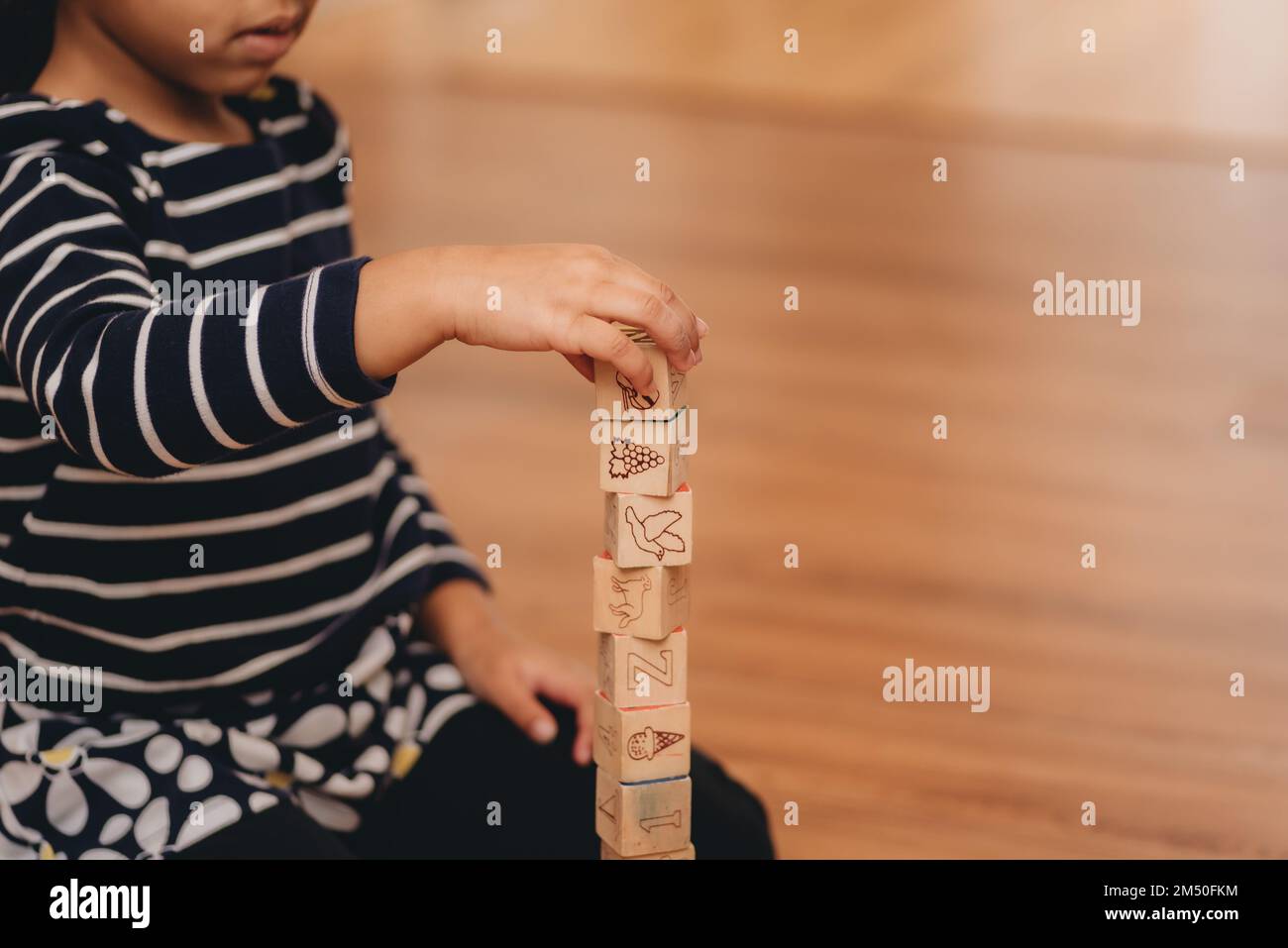 A preschool girl, playing with wooden letter blocks at home on the ...