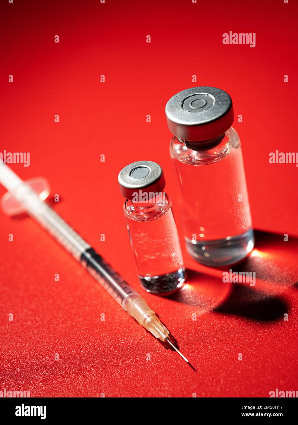 Syringe and drug bottle on red background Stock Photo - Alamy