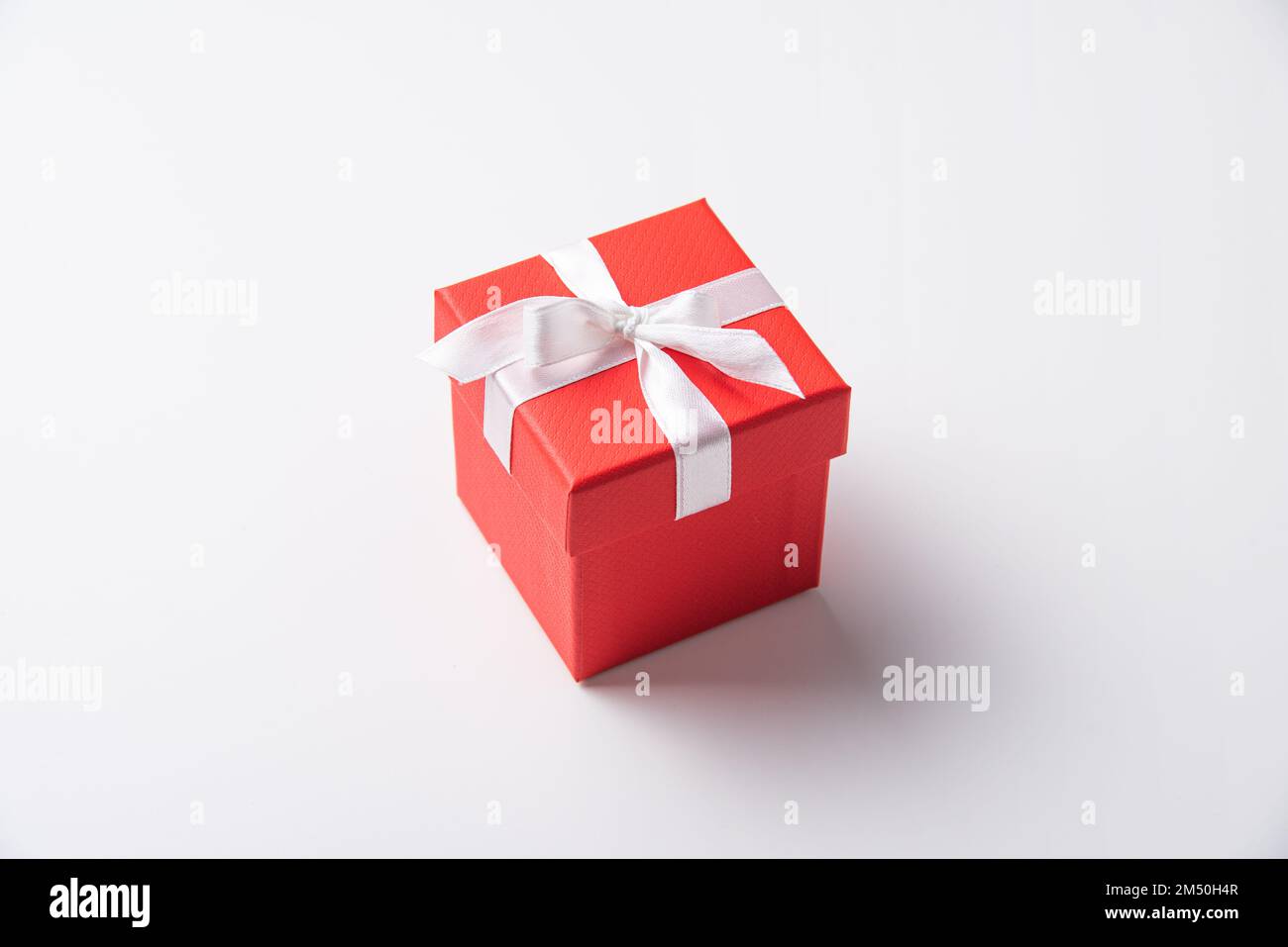 red gift box with white ribbon on white table. Top view and copy space ...