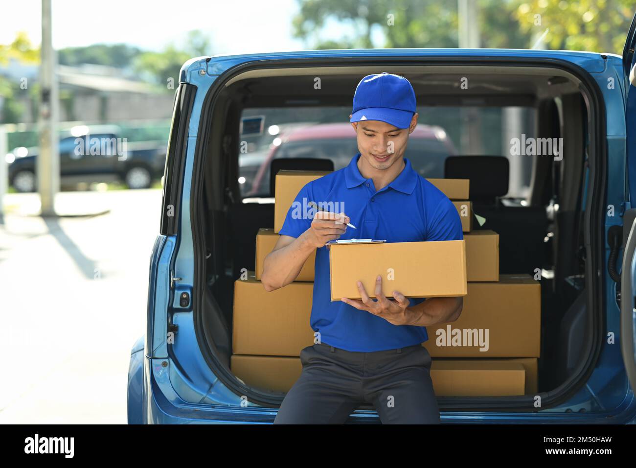 Image of delivery man sitting in open delivery van and checking ...
