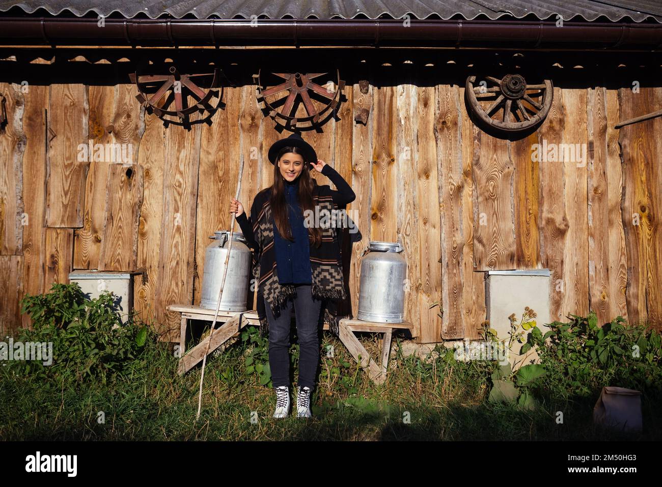 Woman sits on a bench with milk cans on a farm Stock Photo - Alamy
